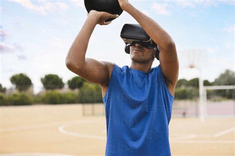Young Man Wearing Vr Headset Throwing Basketball At Sports Court Stock