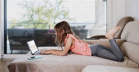 아름다운 소녀는 거실 소파에 누워 서핑 학습 및 의사 소통을 위해 노트북을 사용합니다 그녀는 행복하고 미소 지었다 사진 Unsplash의 세르비아 이미지