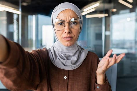 Worried Businesswoman In Hijab Standing In Office And Talking On Video