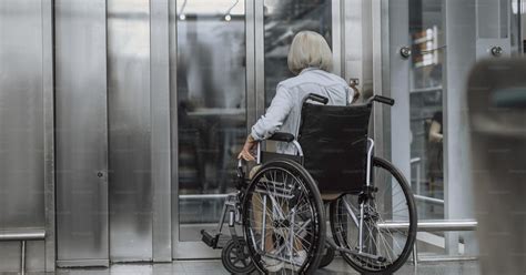 휠체어에 앉아 엘리베이터를 기다리는 동안 늙은 여성의 뒷모습 초상화 왼쪽의 복사 공간 사진 Unsplash의 복사 공간 이미지