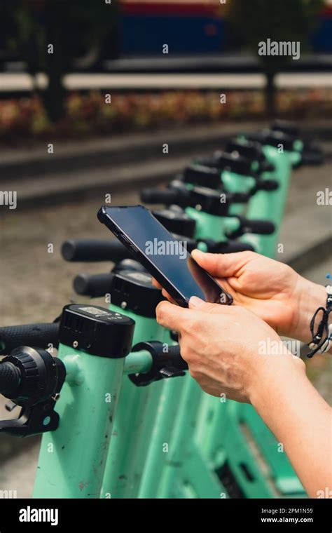 Female Hand Uses Mobile Phone To Scan QR Code On Electric Scooter On The Street On E Scooter