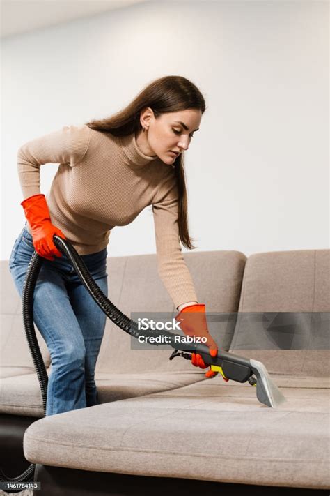 드라이 클리닝 추출기 기계가 물과 세제를 근접 분사하고 있습니다 전문 가정용 청소 서비스 직원이 드라이 클리닝 기계를 사용하여 소파의 먼지와 먼지를 제거하고 있습니다 소파에