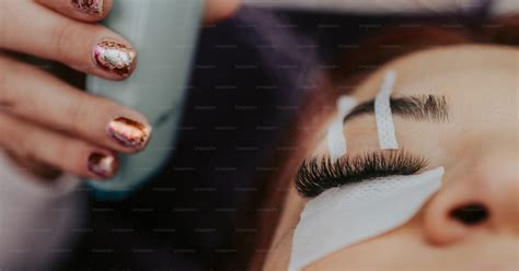 속눈썹 연장 절차에 아름 다운 젊은 여자입니다 화장품과 바디 케어 클로즈업 샷 보호용 안면 마스크를 쓴 여성 미용사 코로나 바이러스는 안전한 개념을 유지합니다 사진