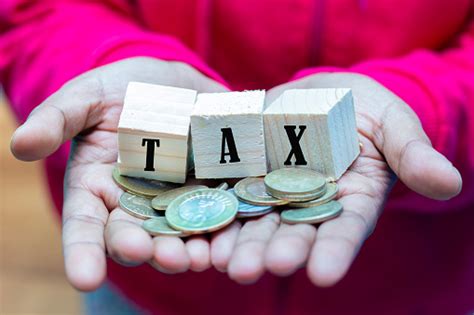 청록색 배경에 Tax라고 적힌 동전과 나무 블록을 들고 있는 손은 금융 세금 및 경제적 책임을 상징합니다 개념에 대한 스톡 사진 및 기타 이미지 Istock