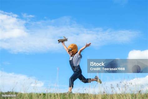 화창한 날에 장난감 비행기를 손에 들고 초원을 뛰어 다니는 귀여운 소녀 푸른 여름 하늘 배경에 골판지 비행기로 노는 행복한 아이 어린 시절의 꿈 상상력 개념 종이 비행기에