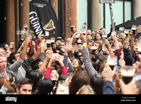 Image People In A Crowd Holding Pints Of Guinness In The Air During The