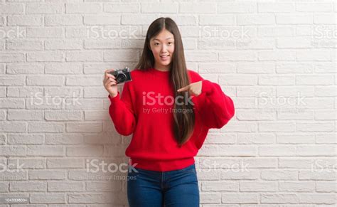 자신에 게 놀라운 얼굴 가리키는 손가락으로 빈티지 카메라를 들고 하는 벽돌 벽을 통해 젊은 중국 여자 가리키기에 대한 스톡 사진 및 기타 이미지 Istock