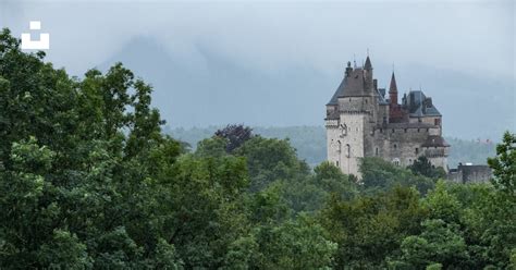 낮에는 파랗고 하얀 하늘 아래 키가 크고 푸른 나무로 둘러싸인 갈색 성 사진 Unsplash의 무료 안시 이미지