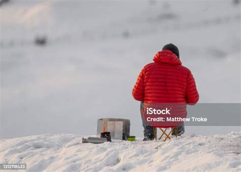 따뜻한 식사와 음료를 유지하기 위해 휴식을 취하는 흰색 눈 덮인 산 언덕에 빨간 코트를 입은 겨울 등산가 겨울에 대한 스톡 사진