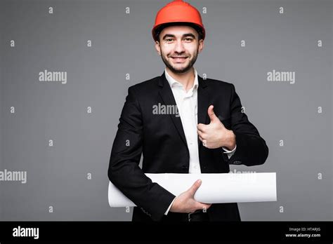 Young Male Architect Wearing Helmet And Holding Blueprints Isolated On White Background Stock