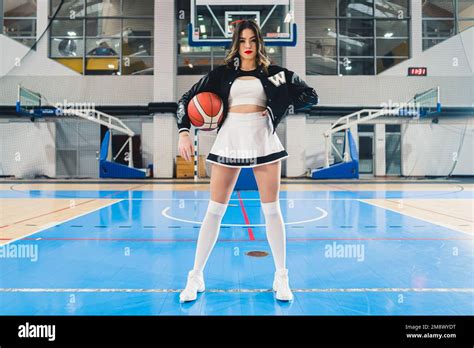 Confident Cheerleader Posing On The Basketball Court With A Ball