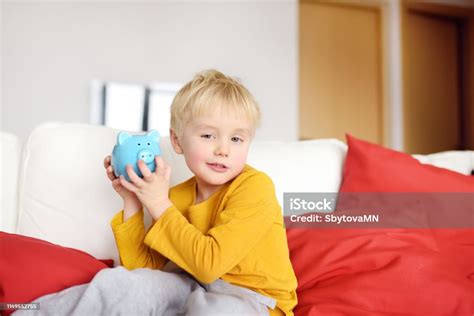 돼지 저금통을 흔드는 어린 소년이 그가 살 수 있는 것을 꿈 꿉 니다 어떻게 돈을 처리 하는 아이를 가르치고 돈 절약 개념입니다 가정 생활에 대한 스톡 사진 및 기타 이미지