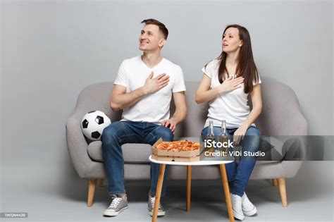 흰색 티셔츠에 커플 여자 남자 축구 팬 응원은 회색 배경에 고립 옆에 보이는 가슴에 손으로 좋아하는 팀 노래 찬송가 지원 사람들 스포츠 가족 레저 라이프 스타일 개념입니다