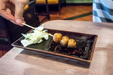 여 자가 나눠 들고 매운 디 핑 소스에 구운된 미트볼의 막대기 사각형 모양에 갈색 도자기 접시에 신선한 양배추와 함께 제공 됩니다 갈색에 대한 스톡 사진 및 기타 이미지