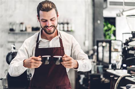 잘 생긴 수염 바리스타 남자 중소 기업 소유자의 초상화 미소와 카페 또는 커피 숍에서 커피 한 잔을 들고 카페에 서있는 남성 바리스타 기업가에 대한 스톡 사진 및 기타