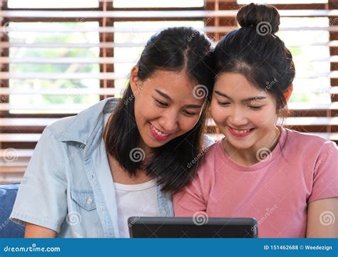 Happy Asian Lesbian Watching Video On Tablet At Sofa In House Lgbtq