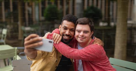 다운 증후군을 앓고있는 청년과 그의 멘토링 친구는 카페에서 야외에서 셀카를 찍고 있습니다 사진 Unsplash의 우정 이미지