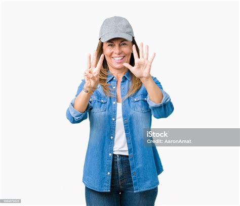 아름 다운 중 년 여자에 스포츠 모자를 쓰고 절연 배경 표시 하 고 자신감과 행복 미소 하는 동안 8 번호 손가락으로 가리키는 8에 대한 스톡 사진 및 기타 이미지 Istock