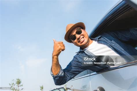 모자를 쓴 여행자가 차를 몰고 차 창 밖으로 몸을 끌어당기고 있습니다 그리고 엄지 손가락이 사진은 자동차로 안전한 여행에 관한 것입니다 차에 대한 스톡 사진 및 기타 이미지