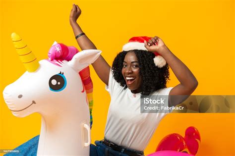 스튜디오에서 산타클로스 모자를 쓰고 무지개 유니콘 플로트에 앉아 있는 아프리카 여성 아프리카에 대한 스톡 사진 및 기타 이미지 아프리카 아프리카 민족 크리스마스