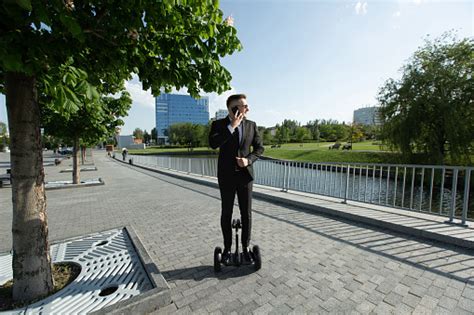 검은 양복을 입은 사업가가 자이로 스쿠터를 타고 전화로 이야기합니다 비즈니스에 대한 스톡 사진 및 기타 이미지 비즈니스