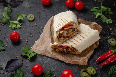 어두운 돌 테이블에 맛있는 샤와르마와 용암 타코 패스트 푸드 레스토랑 패스트 푸드의 건강한 옵션 쇠고기 고기와 야채를 곁들인 맛있는 신선한 랩 샌드위치 전통 중동 스낙