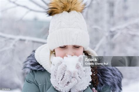 따뜻한 옷을 입은 한 소녀가 겨울 공원에서 장갑을 끼고 눈을 들고 있다 겨울 라이프 스타일 초상화 2월에 대한 스톡 사진 및
