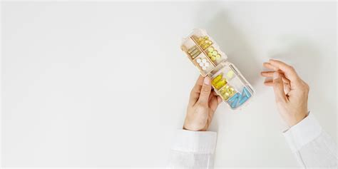 흰 테이블에 비타민과 의약품을 매일 섭취하기위한 알약 상자 상단보기 여성의 손에 열린 플라스틱 용기에 다른 캡슐과 정제 아름다움과 건강을위한 라이프 스타일 플랫 레이 건강