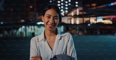 패션 사무복을 입은 성공적인 젊은 아시아 사업가는 밤에 도시의 현대 도시에서 야외에 혼자 서서 행복하게 웃고 카메라를 바라보고 있다 이동 중 비즈니스 및 통근 개념 사진