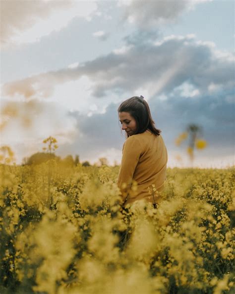 무료 사진 유채 밭에 서 있는 노란 스웨터를 입은 예쁜 갈색 머리