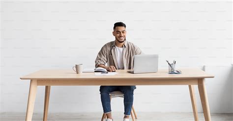 현대 사무실에서 노트북 컴퓨터로 일하는 중동 남성 매니저 책상에 앉아 Pc를 사용하는 쾌활한 남자 키보드로 화면 타이핑을 보고 원격 작업을 즐기고 전신 길이 사진