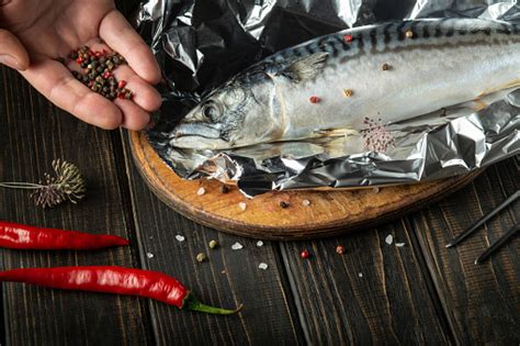 요리사는 부엌 테이블에서 맛있는 점심을 준비하기 전에 고등어 생선에 향기로운 향신료와 후추를 추가합니다 건강한 생활방식에 대한