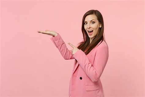 자 켓을 입고 흥분 된 젊은 여자의 초상화는 입을 열어 손으로 가리키는 검지 손가락 옆에 파스텔 핑크 배경에 고립 사람들은 진심으로 감정 라이프 스타일 개념입니다 복사