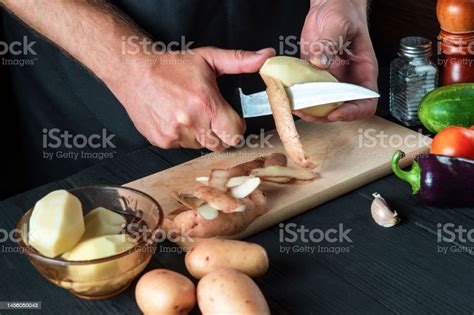 요리사가 굽거나 감자 튀김을 위해 감자 껍질을 벗기고 있습니다 감자 요리 요리용 메뉴 요리 건강 식품에 대한 검은색 배경 개념