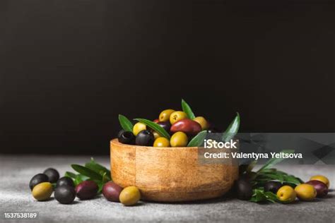 배경에 녹색 빨간색 검은색 올리브 세트 그릇에 담긴 다양한 종류의 올리브와 신선한 올리브 잎을 곁들인 올리브 오일 진미지중해식