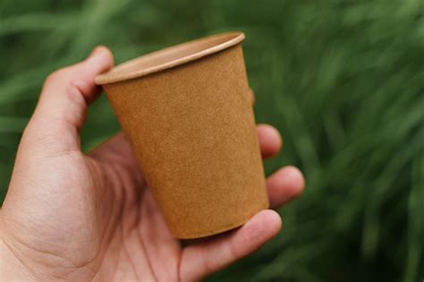 고립된 친환경 천연 커피 컵을 닫습니다 녹색 잔디 배경에 손에 일회용 생태 기구 지구의 지속 가능성 대나무와 바가스 섬유로 만든 골판지 유리 카드보드에 대한 스톡 사진 및