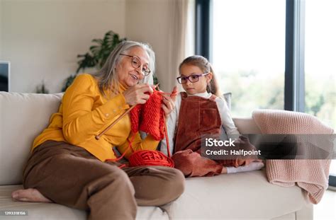 할머니와 함께 소파에 앉아 집에서 실내에서 뜨개질을 하는 법을 배우는 어린 소녀 2명에 대한 스톡 사진 및 기타 이미지 2명 가족 노인 Istock