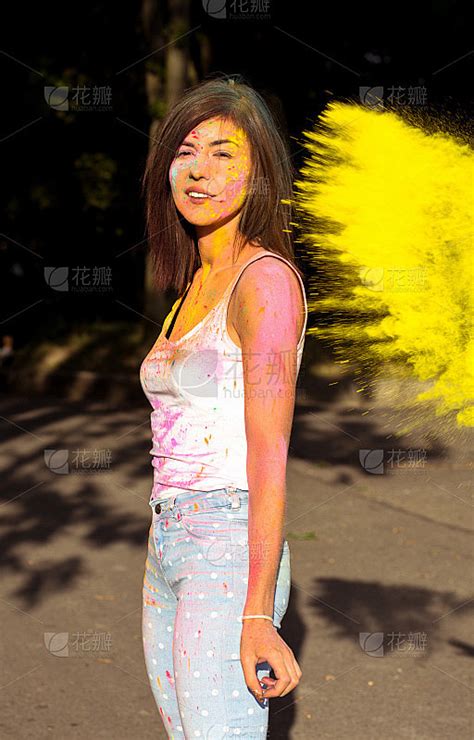 可爱的短头发年轻女子玩爆炸黄色胡里节油漆