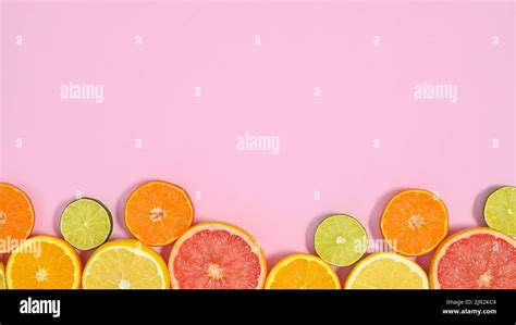 Sliced Citrus Fruits On Bottom Of Pastel Pink Background With Copy