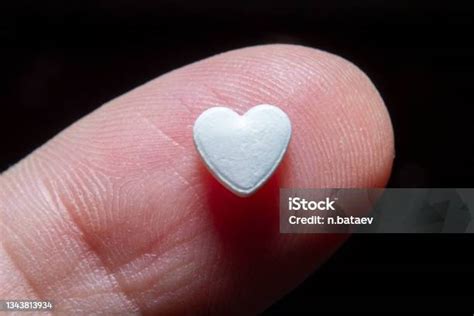 흰 하트 모양의 알약으로 손가락 끝을 클로즈업합니다 심장 혈관 및 폐에 대한 약 높은 배율에서 부드러운 초점에 태블릿의 클로즈업 개념에 대한 스톡 사진 및 기타 이미지
