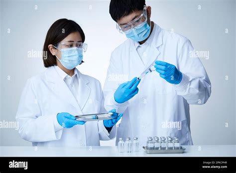 Man And Woman In Lab Coat Inserting Syringe Into Bottle Stock Photo Alamy