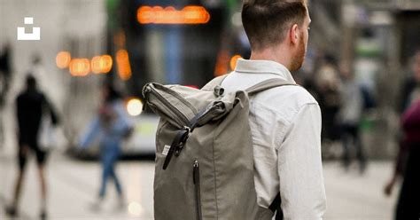 흰색 드레스 셔츠와 검은 바지를 입은 남자가 낮 동안 보도를 걷고 있는 검은 배낭을 들고 있다 사진 Unsplash의 무료 부어크 스트리트 몰 이미지