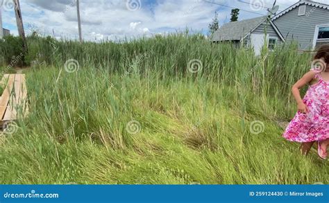 Menina Segurando Uma Boneca E Caminhando Em Um Campo De Grama Longo Em