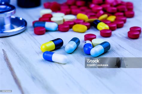 항생제는 복사 된 간격으로 흰색 나무 질감 배경에 파란색 알약 노란색 빨간색 또는 캡슐을 포함합니다 건강한 용기 항생제 및 위험한 약물에 약물 0명에 대한 스톡 사진 및