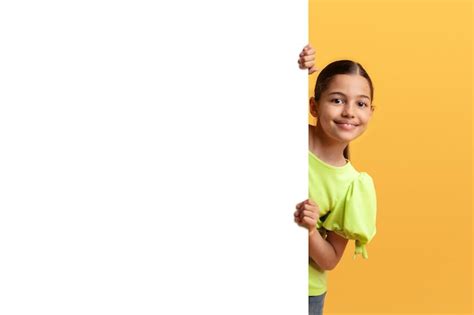 Улыбающаяся девочка подросток прячется за чистым белым плакатом Премиум Фото