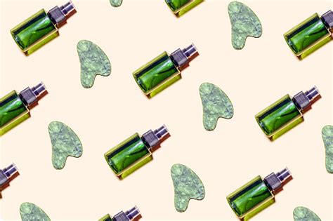 베이지색 배경에 녹색 화장품 병과 옥 얼굴 마사지기의 패턴 얼굴 마사지 노화 방지 리프팅 및 토닝 치료 지압 메이크업 화장품에