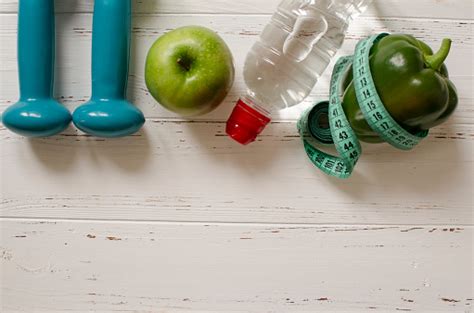 2 아령 물 그린 애플 텍스트에 대 한 공간을 가진 백색 나무 배경에 센티미터의 병 0명에 대한 스톡 사진 및 기타 이미지