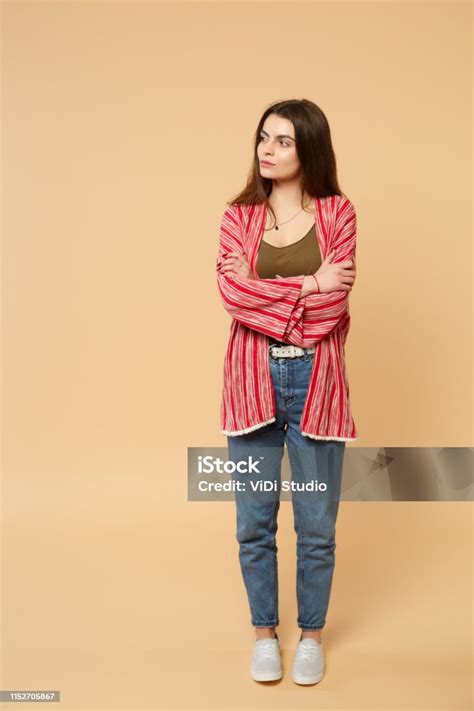 옆을 찾고 캐주얼 옷에 매력적인 젊은 여자의 초상화 손을 잡고 스튜디오에서 파스텔 베이 지 배경에 고립 교차 사람들은 진심으로 감정 라이프 스타일 개념입니다 복사 공간을