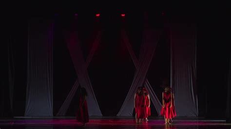 Performers On A Dark Stage With Dramatic Red Lighting And Abstract