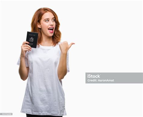 고 행복 얼굴 미소와 측면까지 손가락으로 보여주는 격리 된 배경 위에 아메리카 합중국의 패스포트를 들고 젊은 아름 다운 여자 가리키기에 대한 스톡 사진 및 기타 이미지